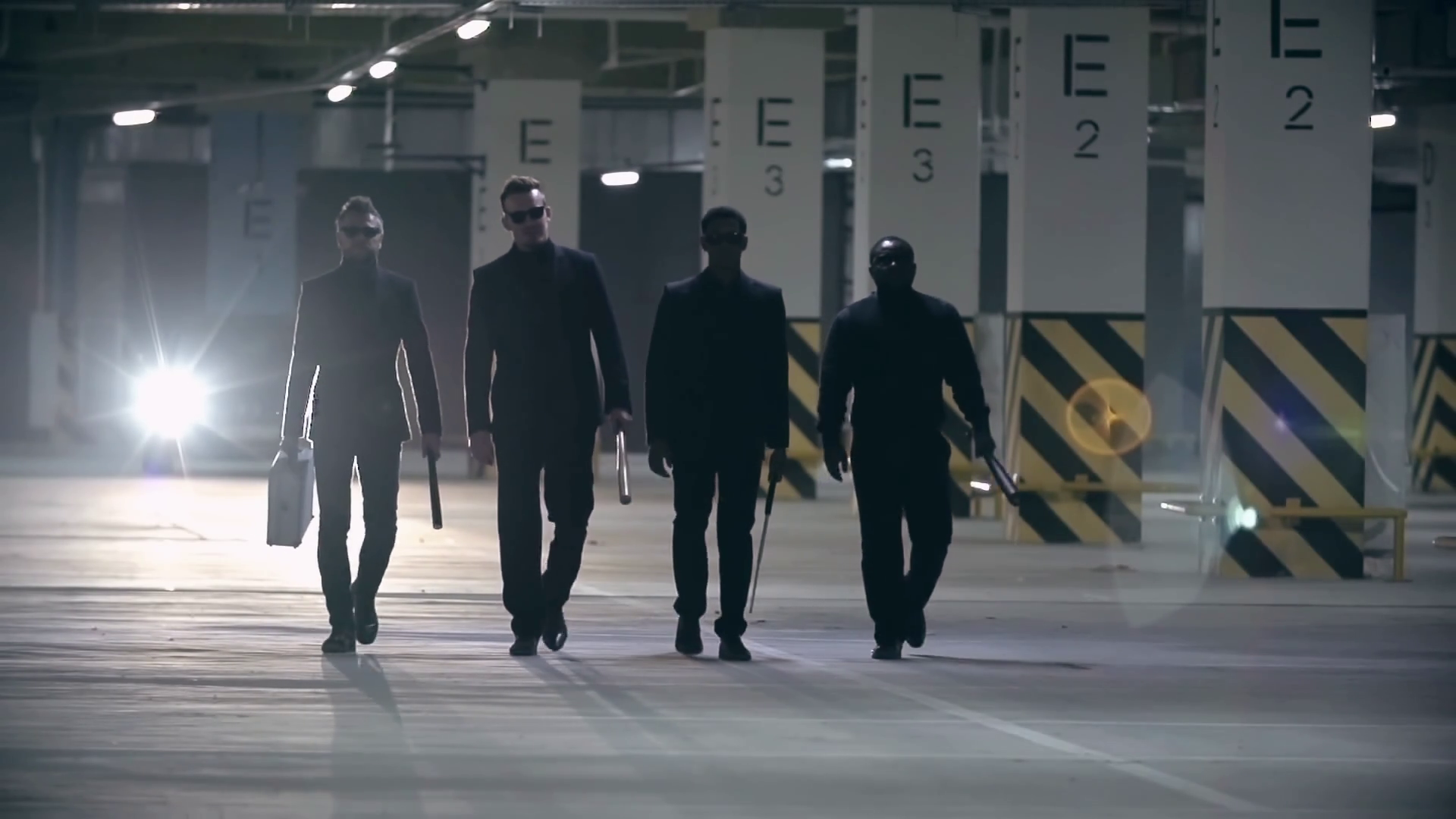 Four men dressed like gangsters walking together with baseball bats ...