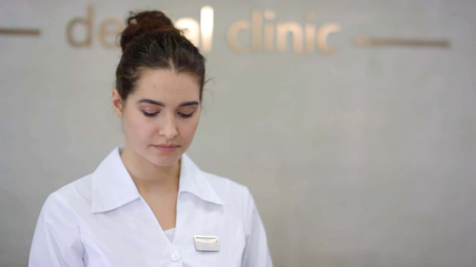 Medium shot of cheerful young female medical receptionist greeting ...