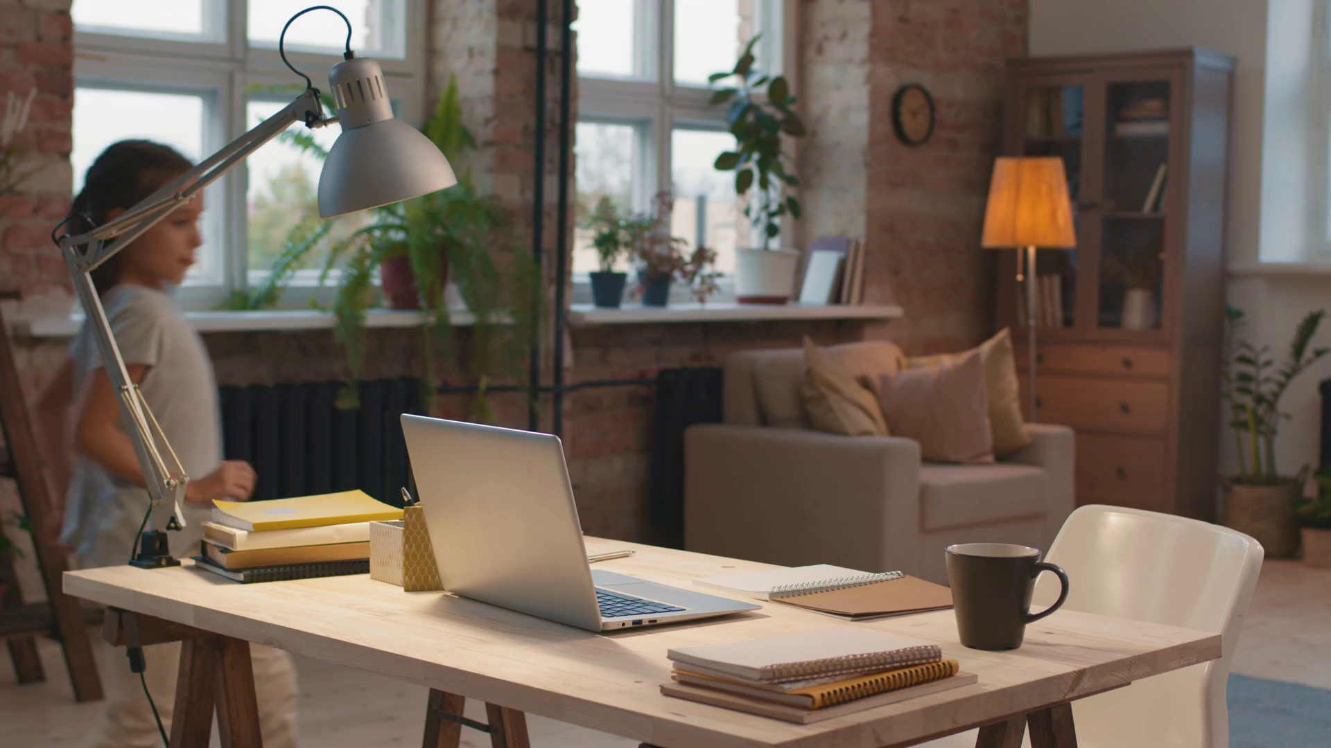 Medium shot with slowmo of little girl sitting down at desk in living ...