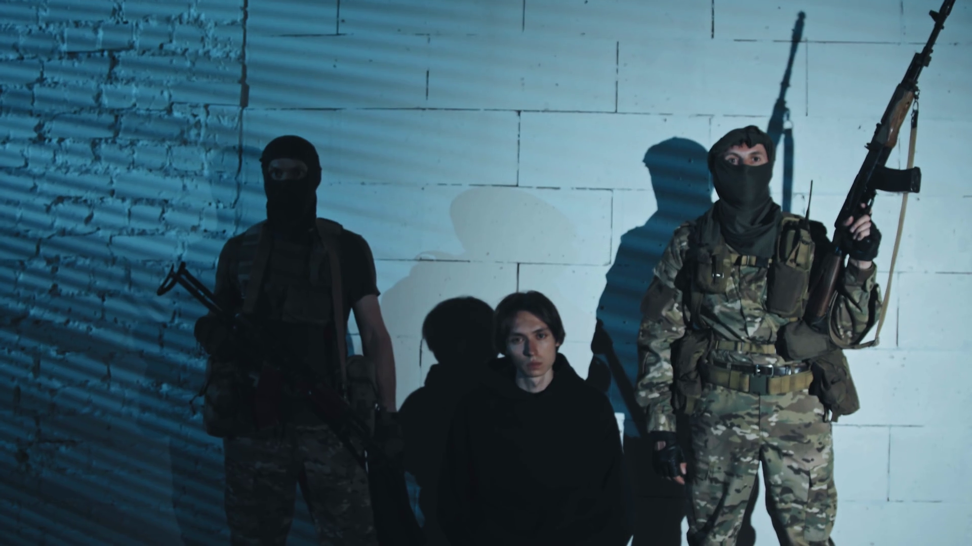 Portrait dolly-in shot of man being held hostage by armed terrorists in ...