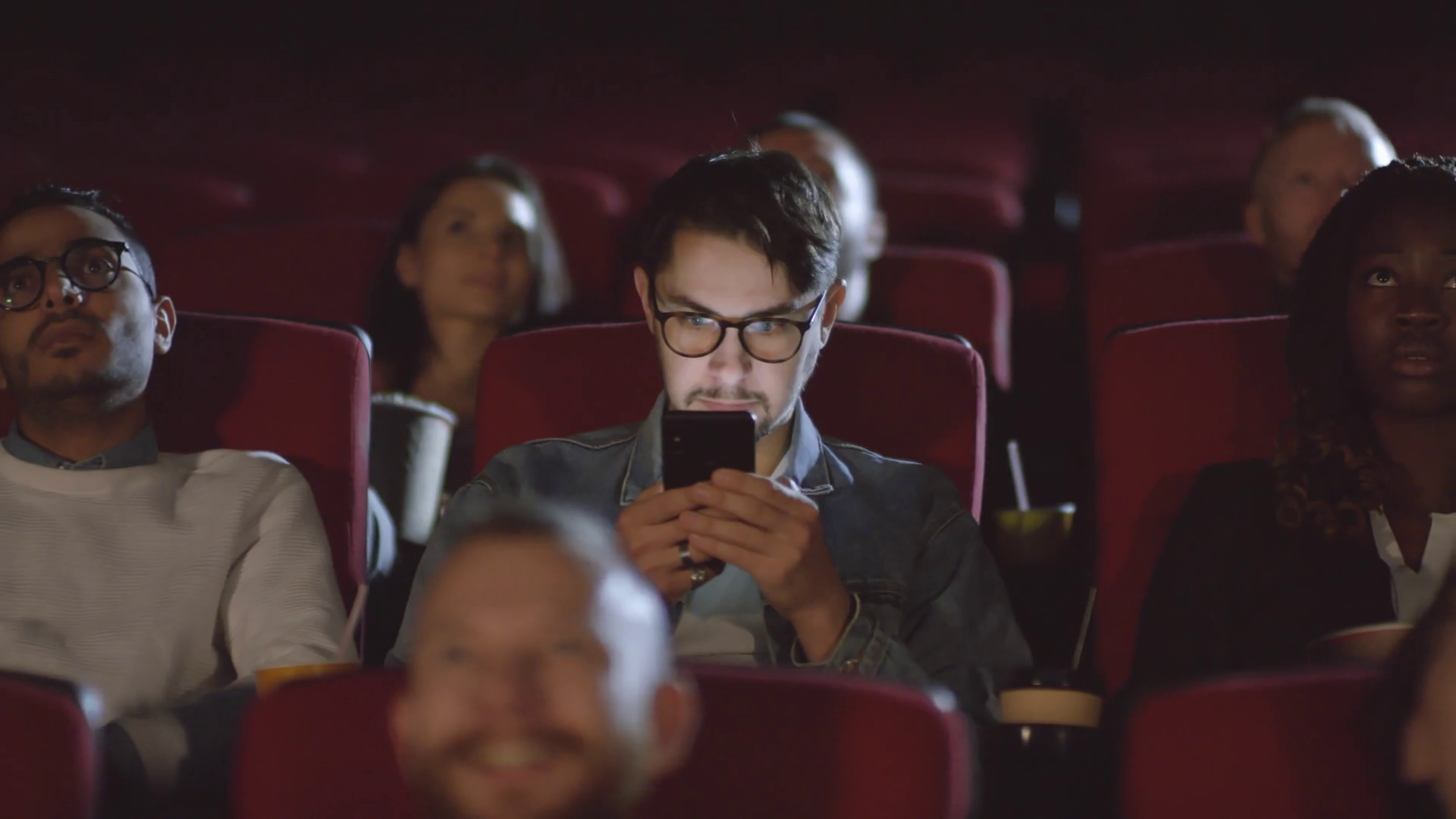 Tracking shot of bearded man in glasses using cell phone in movie ...