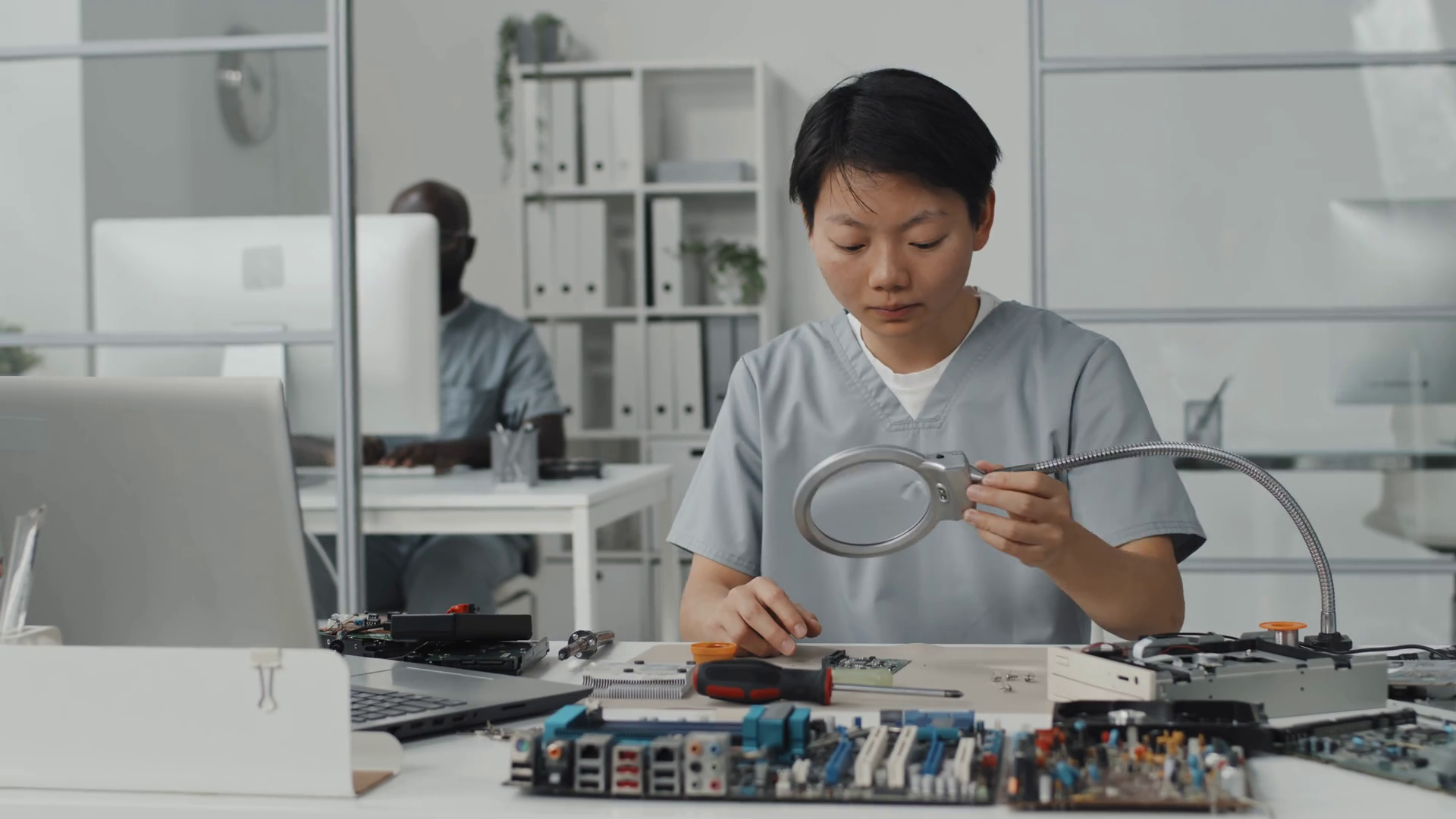 Asian female engineer sitting at desk in laboratory and examining chip ...