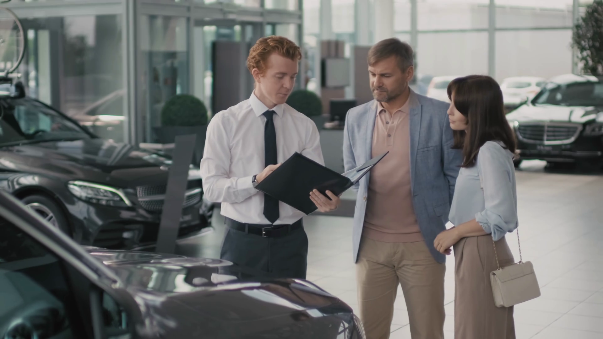 Tracking of young dealership salesman in formal attire holding folder ...