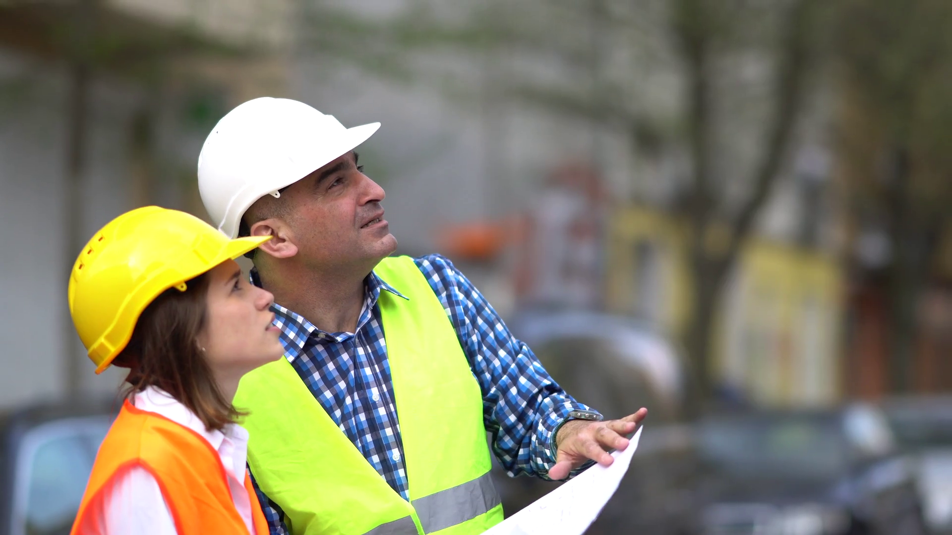 Male and female architects wearing protective vests and hardhats ...