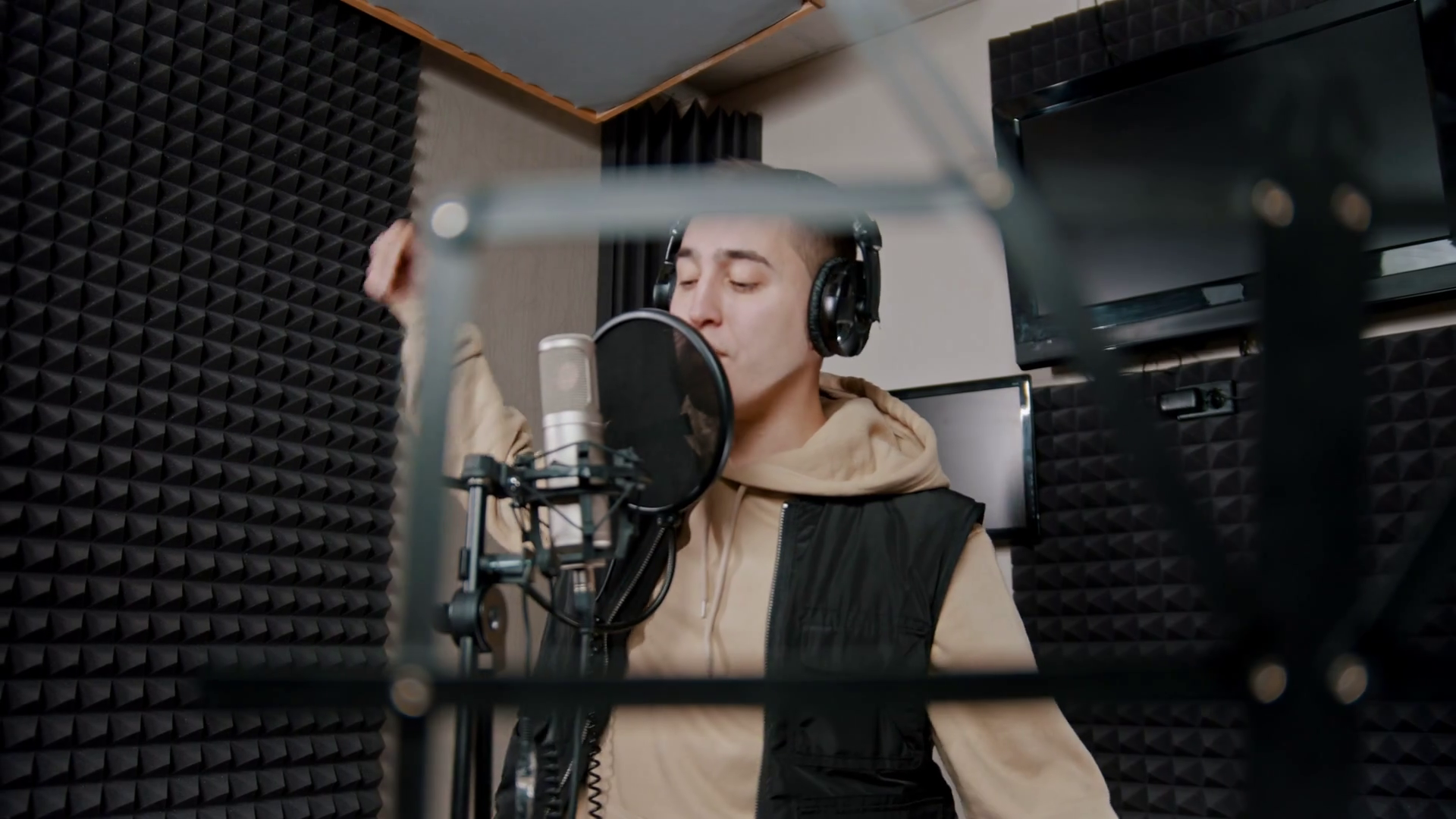 A man rapper recording his track in the studio actively gestures while ...