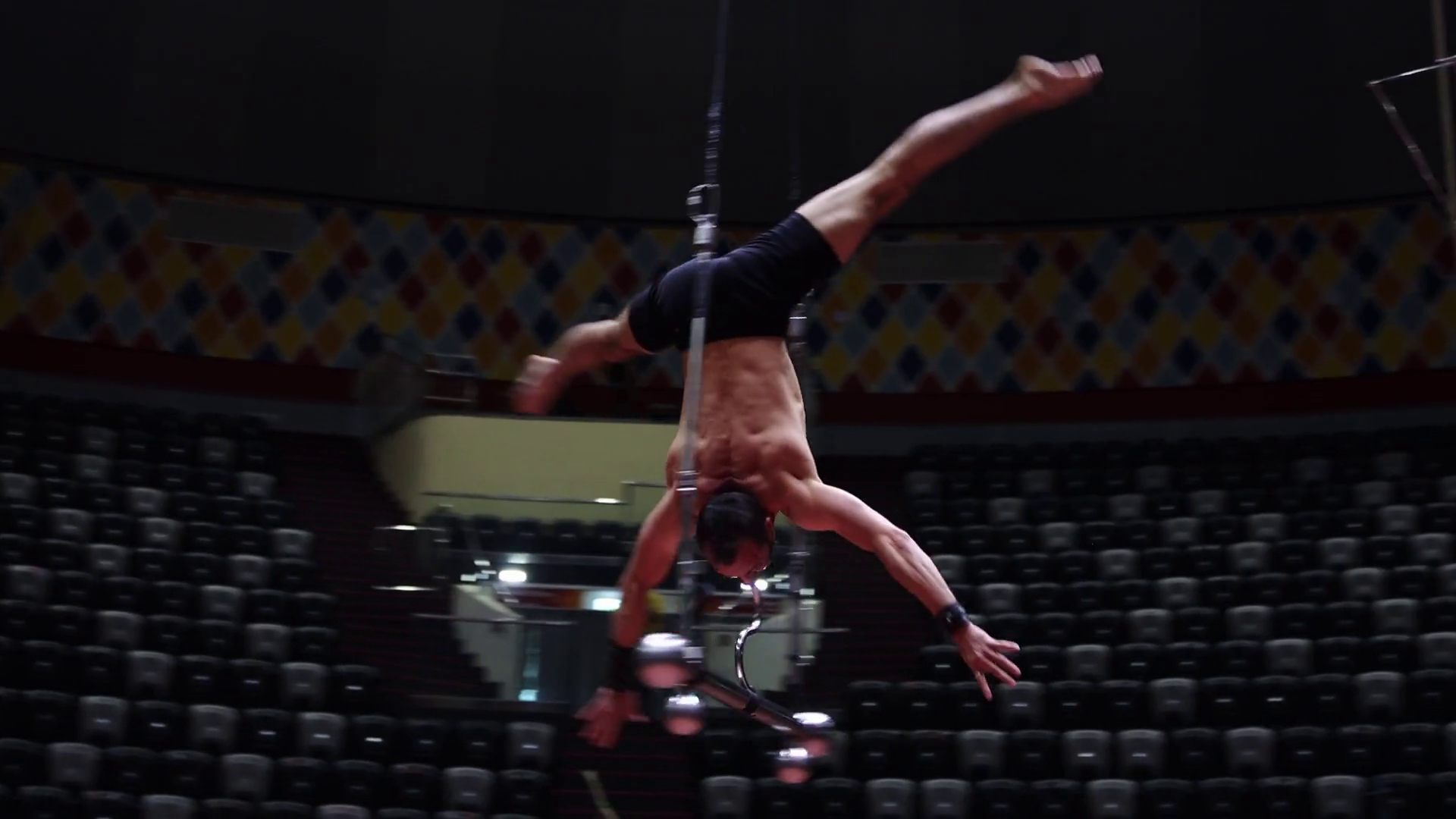 An acrobatic man showing a performance on the flying bar at circus ...
