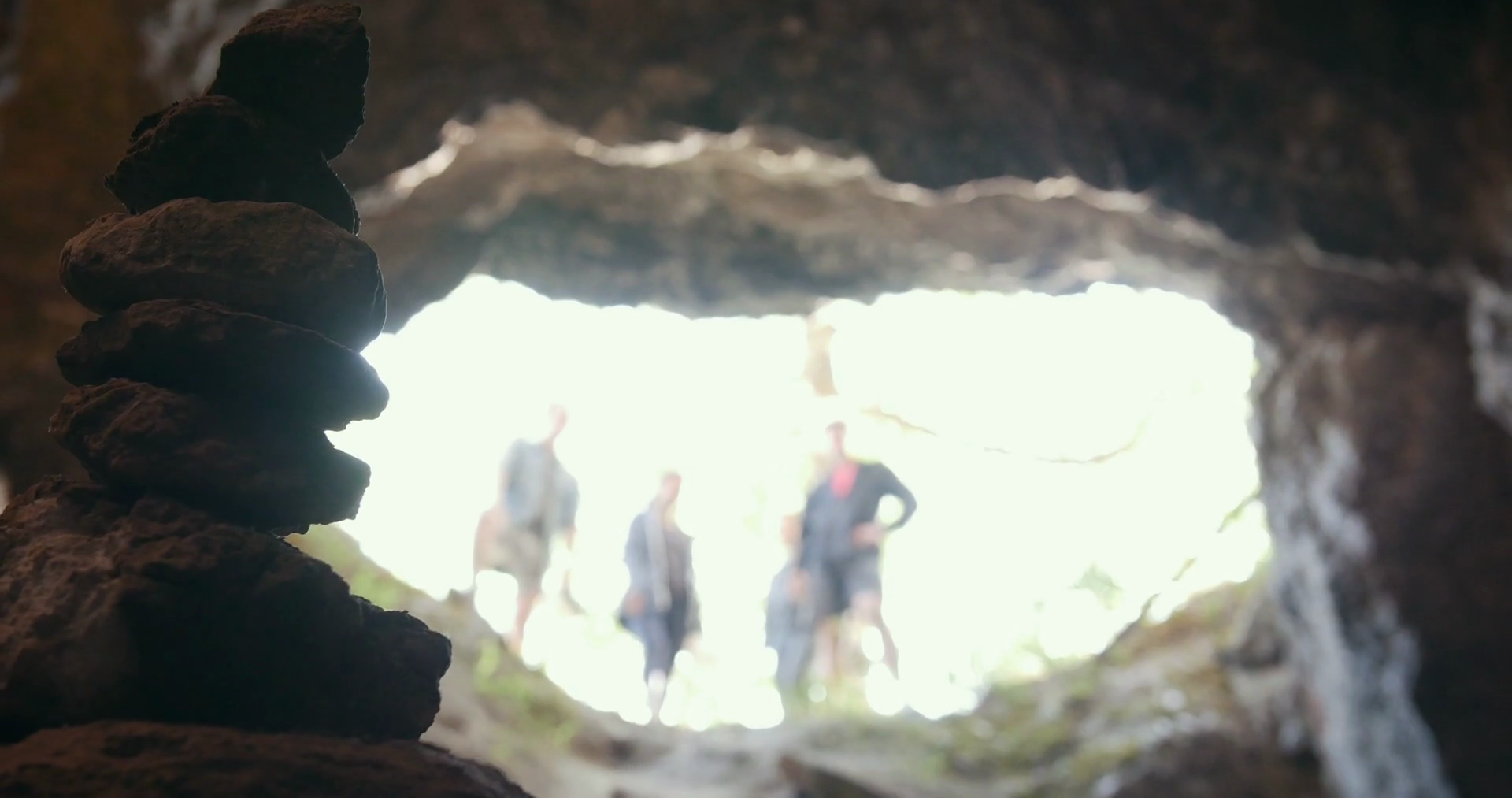 Handmade stone tower in cave in front of group of friends in helmets ...