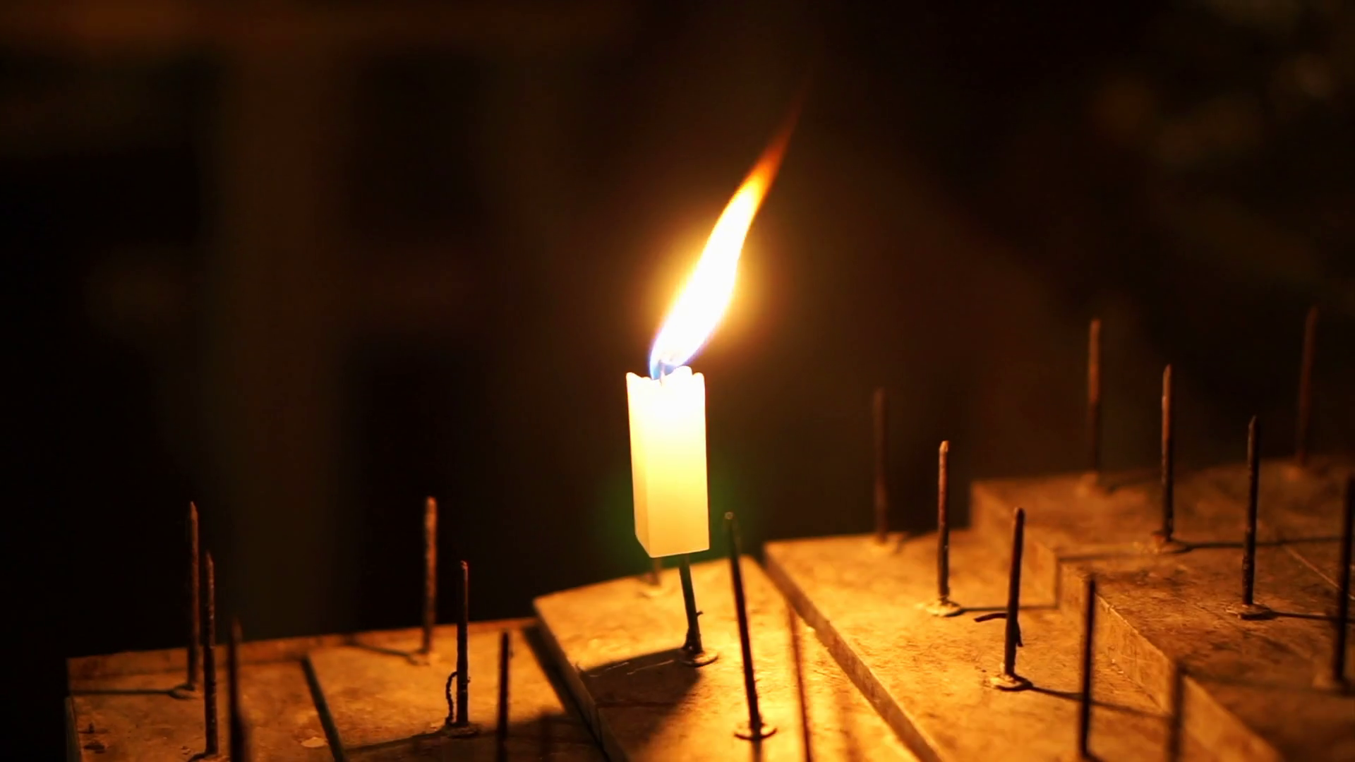 Single candle lit in the dark. Moving flame on sacred stand. Abstract ...