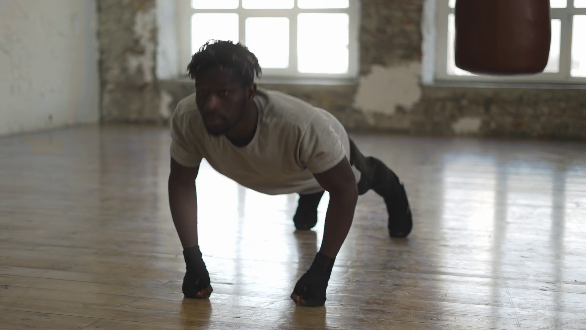 Boxer doing push-ups on the floor while working out in old light ...