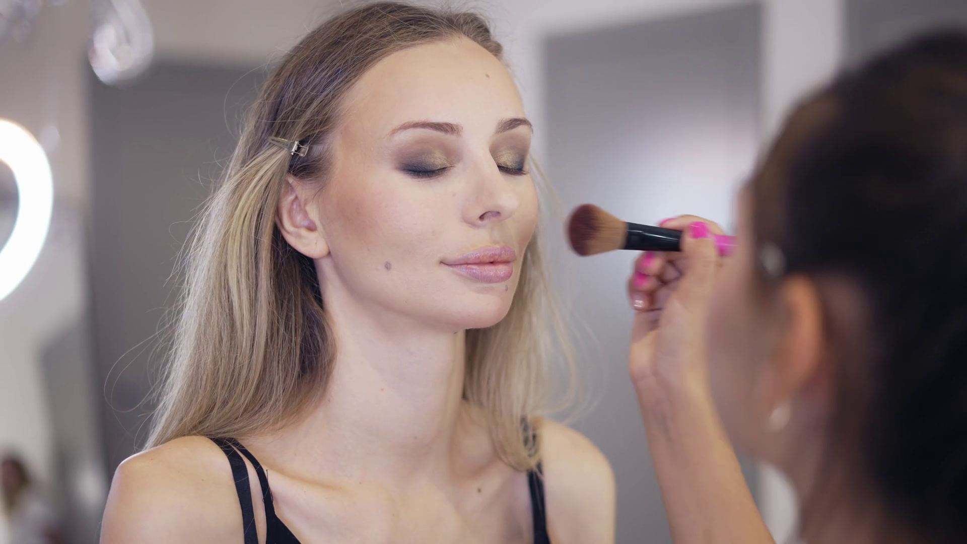 The make-up artist applies the powder on the surface of the young ...