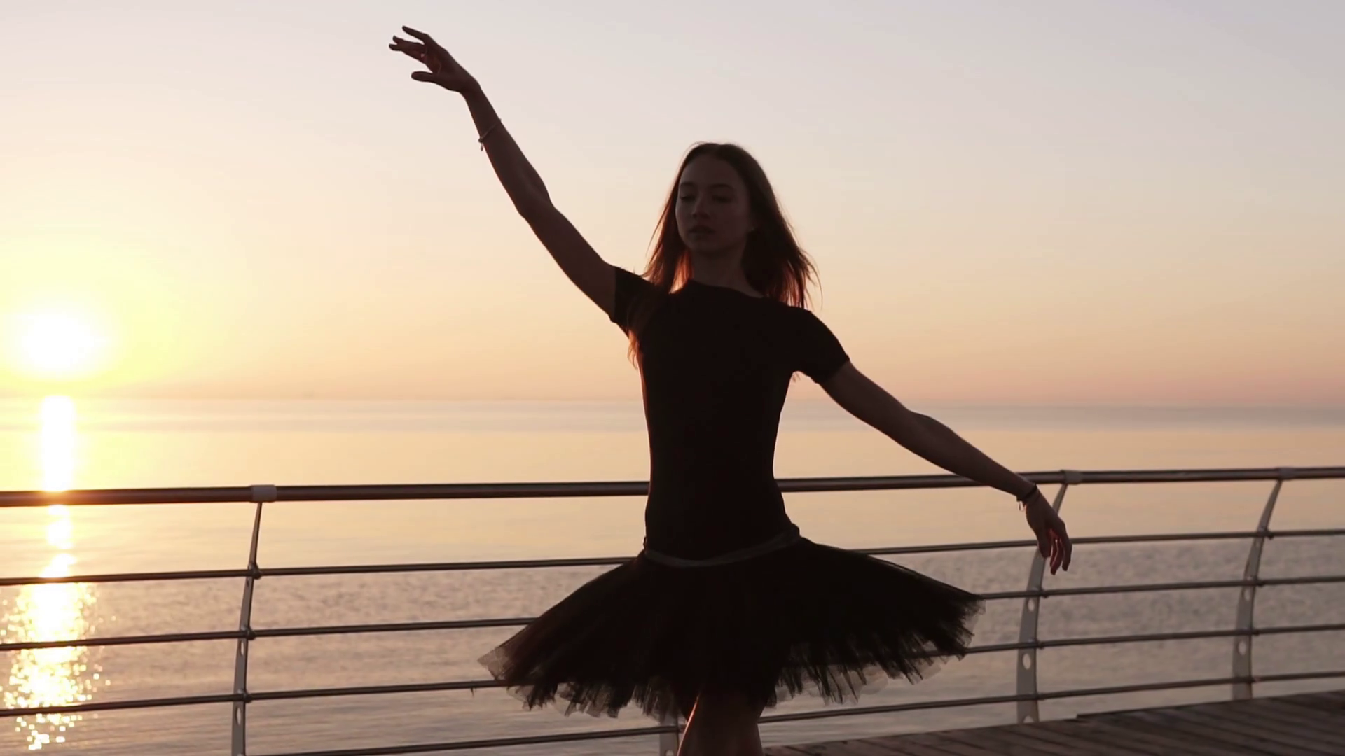 A ballerina practicing a ballet dance near the sea. Preparing and doing ...