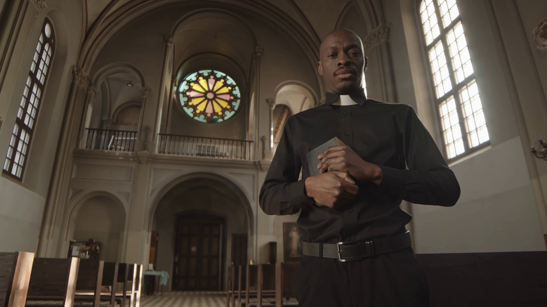 Low angle view of young bald African-American priest wearing black ...