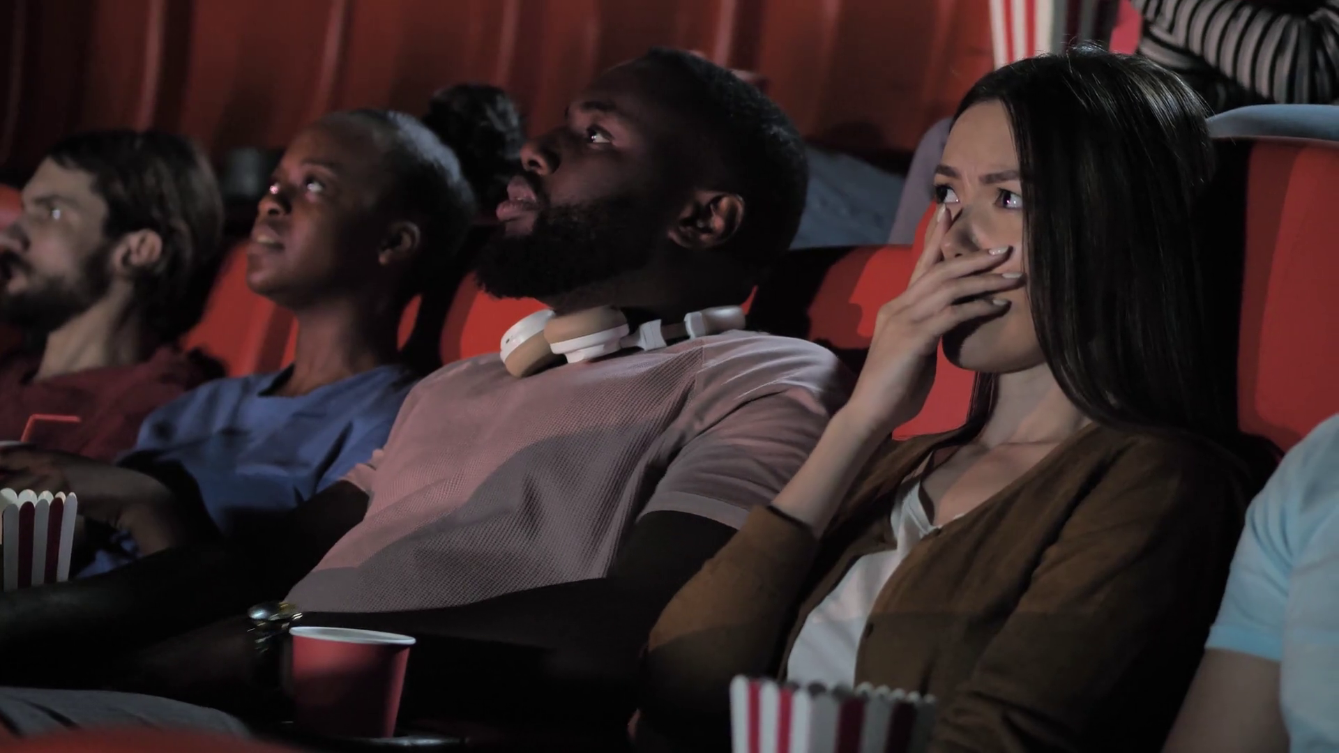 Close-up of diverse audience enjoying scary movie in cinema theater ...