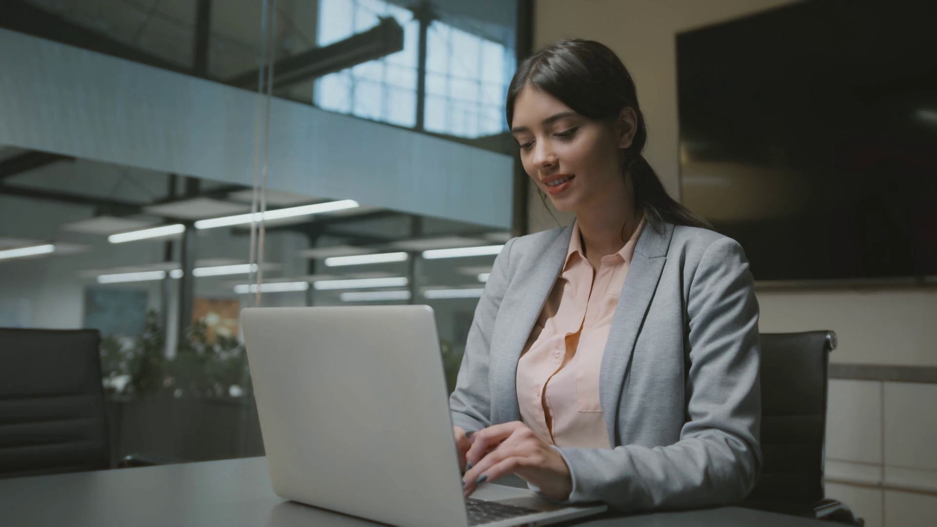 Young confident business lady in formal wear typing on laptop at ...