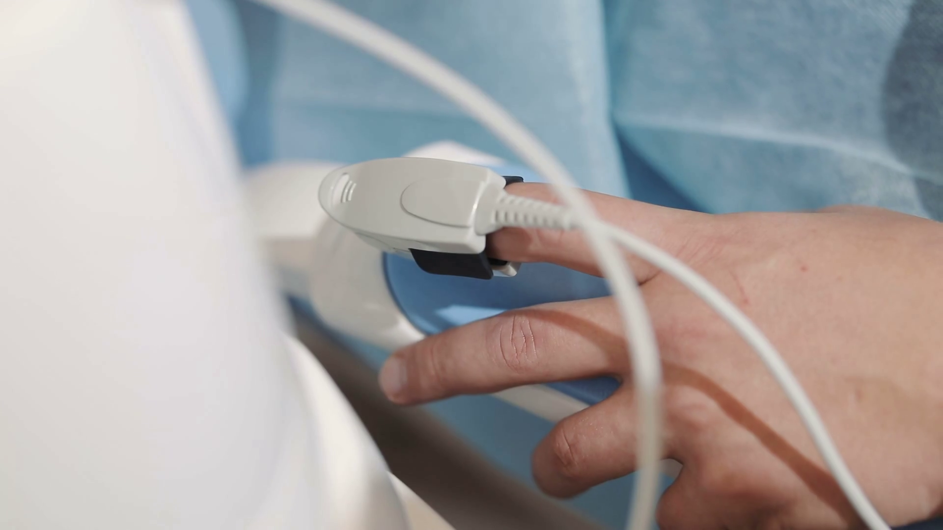 Heart rate monitor on patient's hand in operating room. Cardiograph on ...