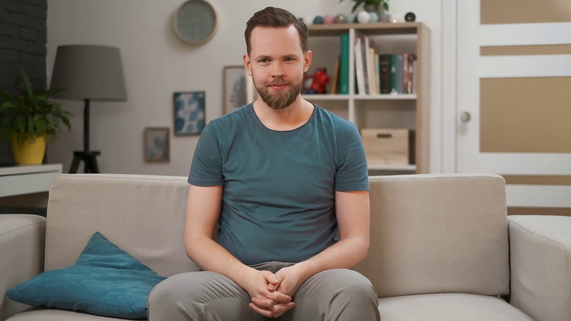 Portrait of a handsome man sitting on a couch at living room, looking ...