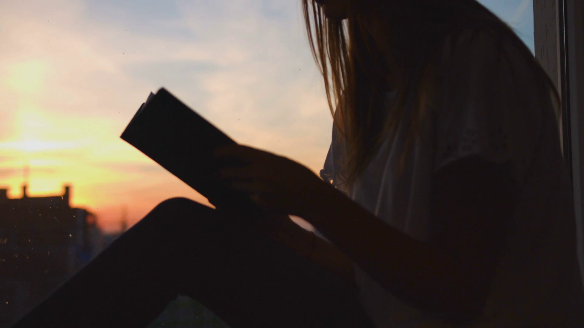 Portrait of young woman watching through the window on sunset and ...