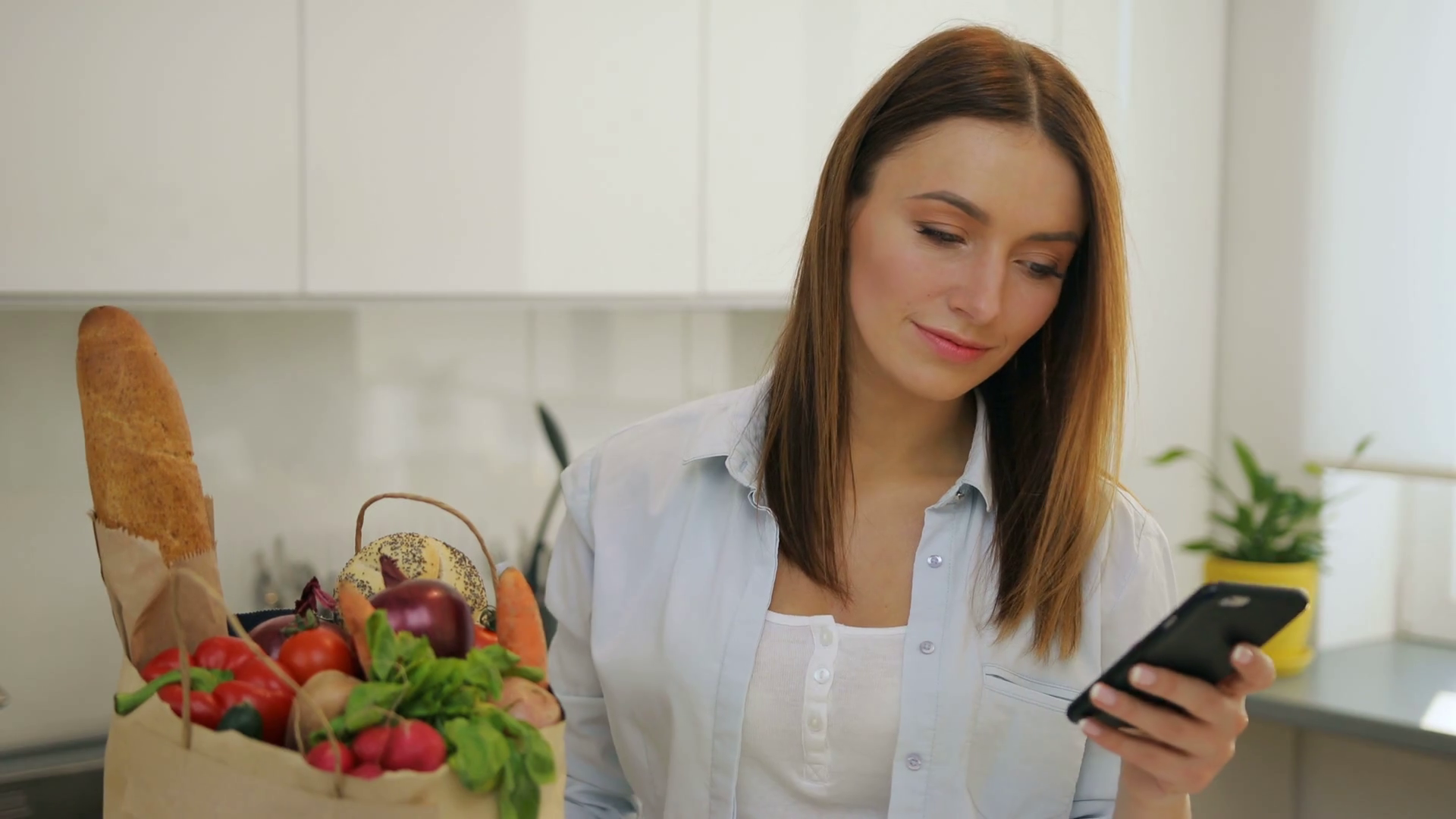 Woman came back home from grocery shopping texting on her cellphone ...