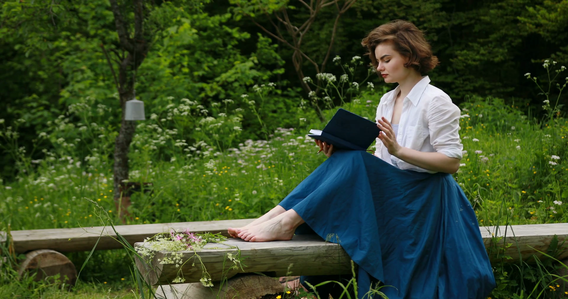 Young girl writing into her diary, in the park. Women at the park ...