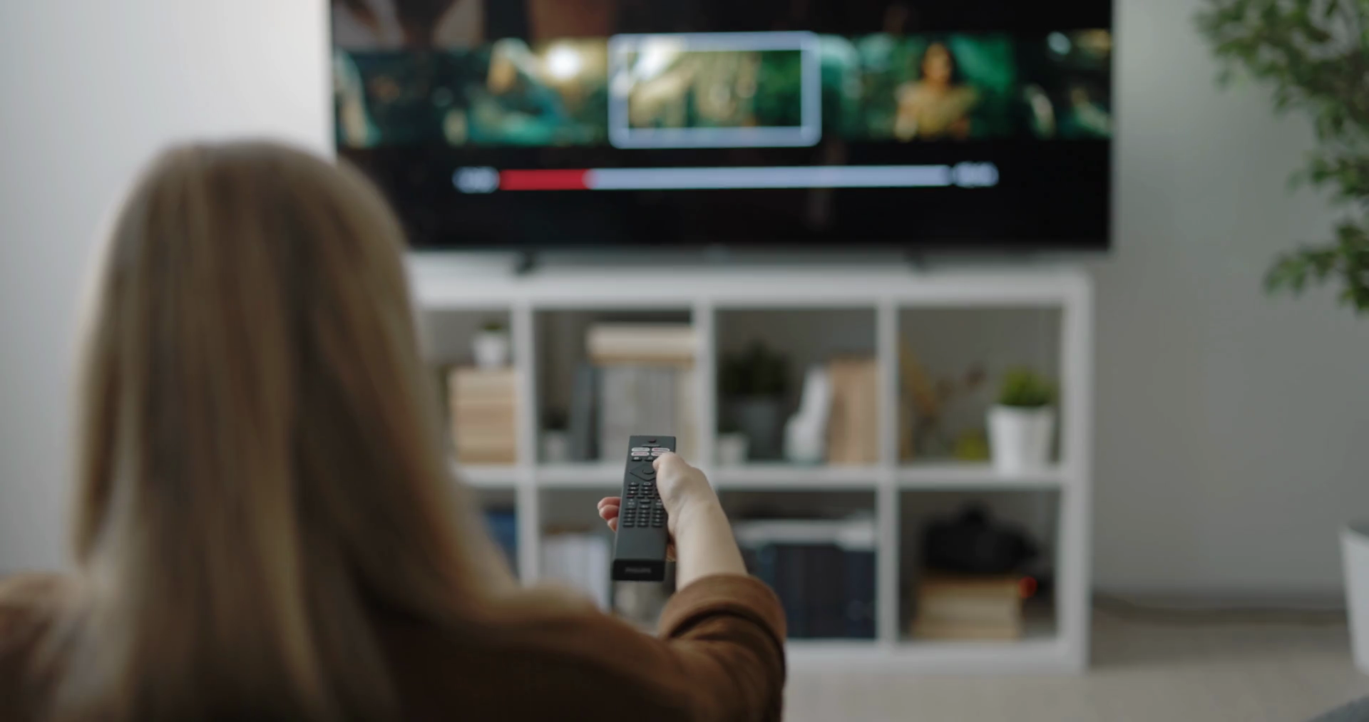 Back view of caucasian woman with blond hair sitting on comfy couch and ...