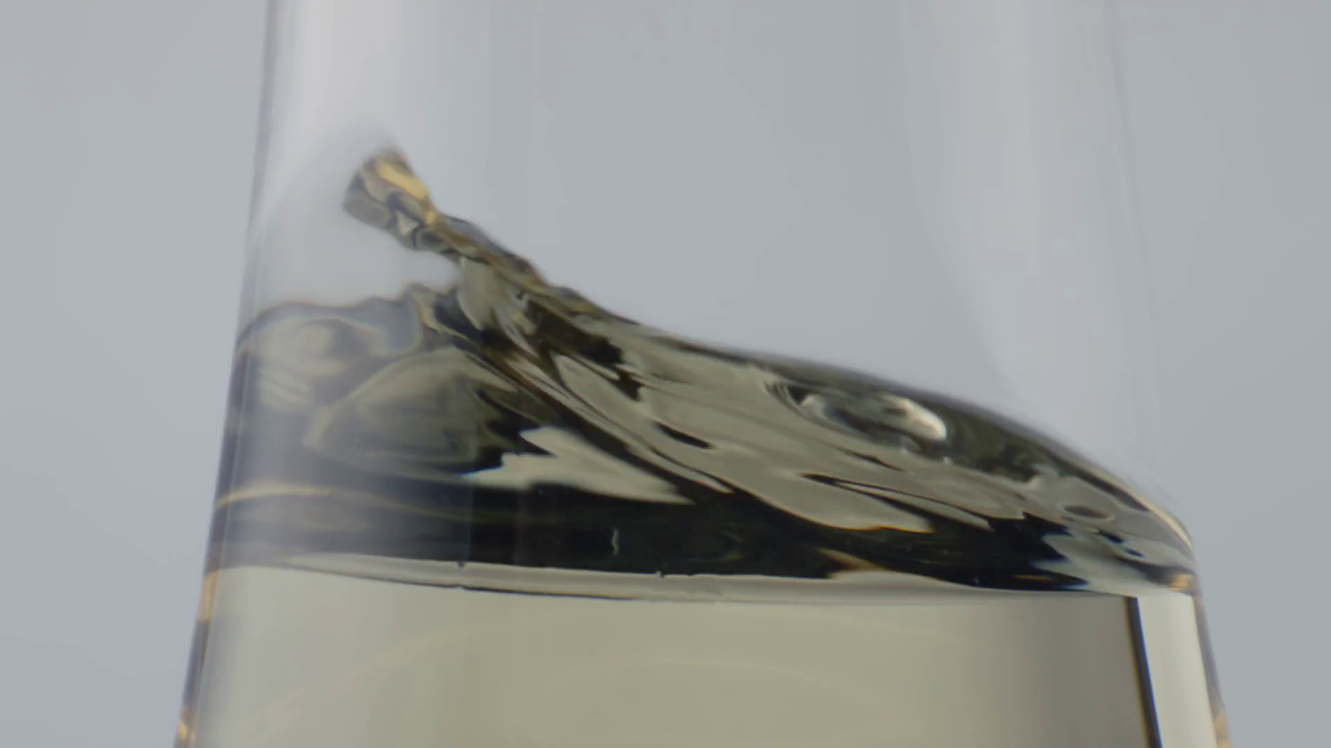 Chardonnay wine swirling in transparent glass super slow motion. Golden ...