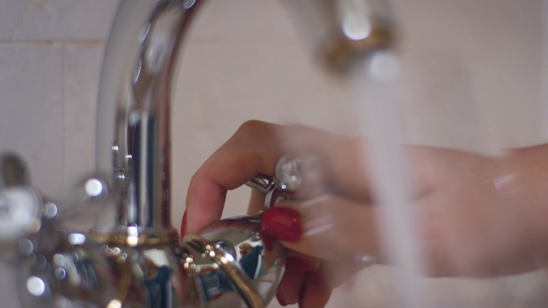 Female hand turning knob on kitchen faucet and pouring water into glass ...