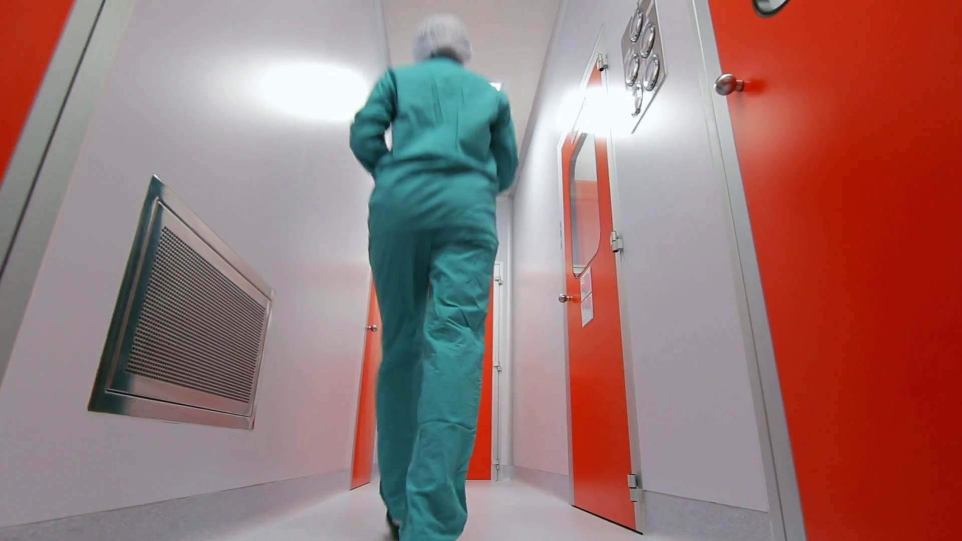 Female scientist in blue uniform walking corridor. Back view of woman ...