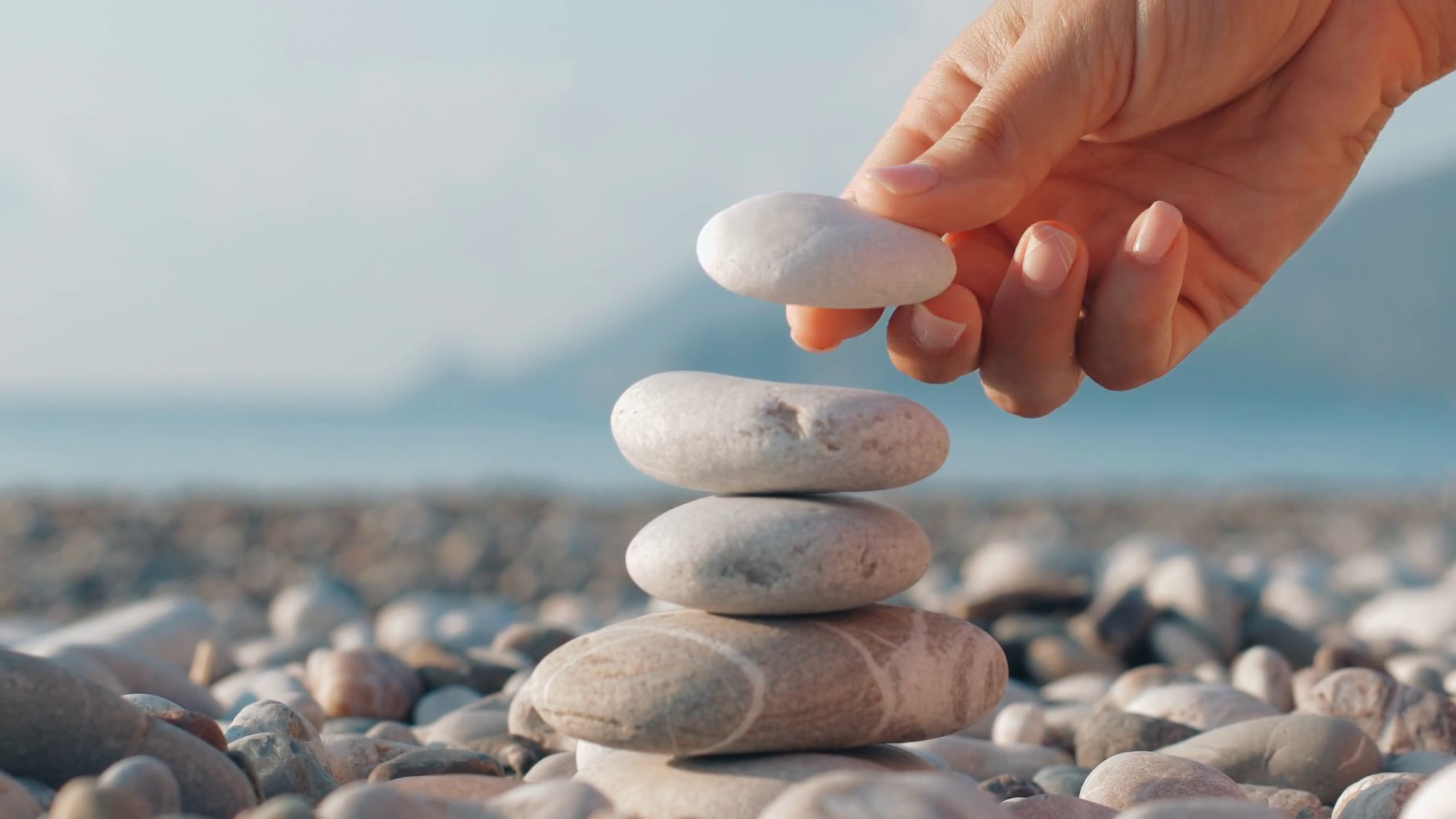 Hand making stone tower on sea beach. Close up of stack of balanced ...