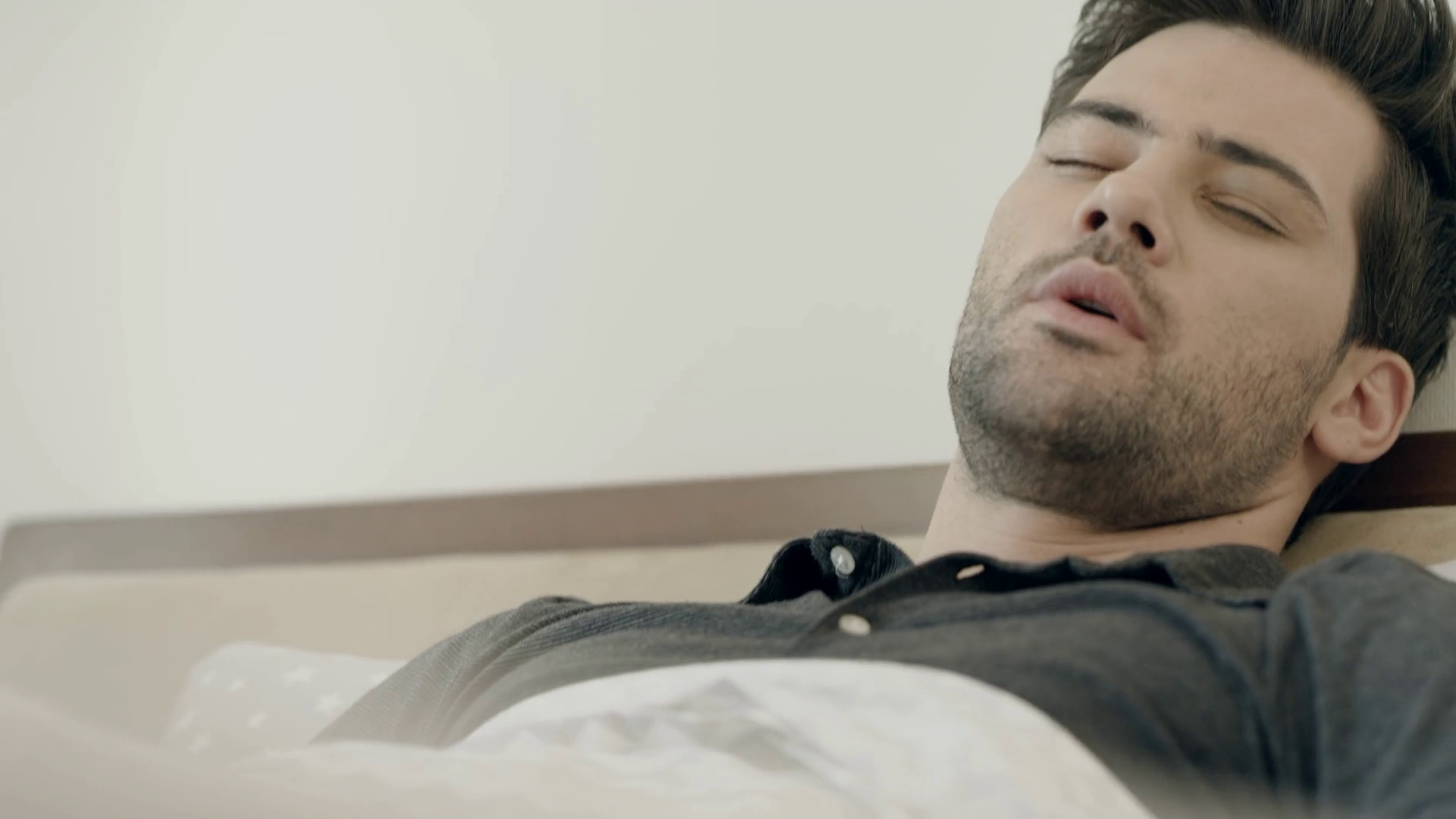 Handsome man waking up in morning. Happy man stretching on bed in house ...