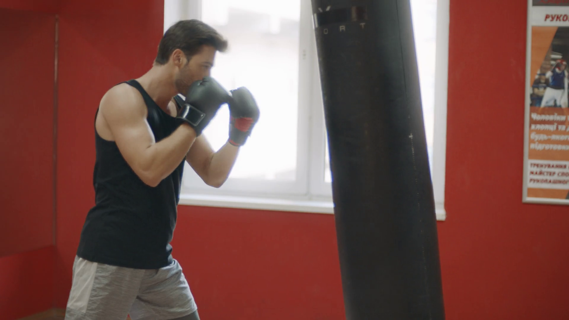 Sport man punching boxing bag at fight training. Serious boxer man ...