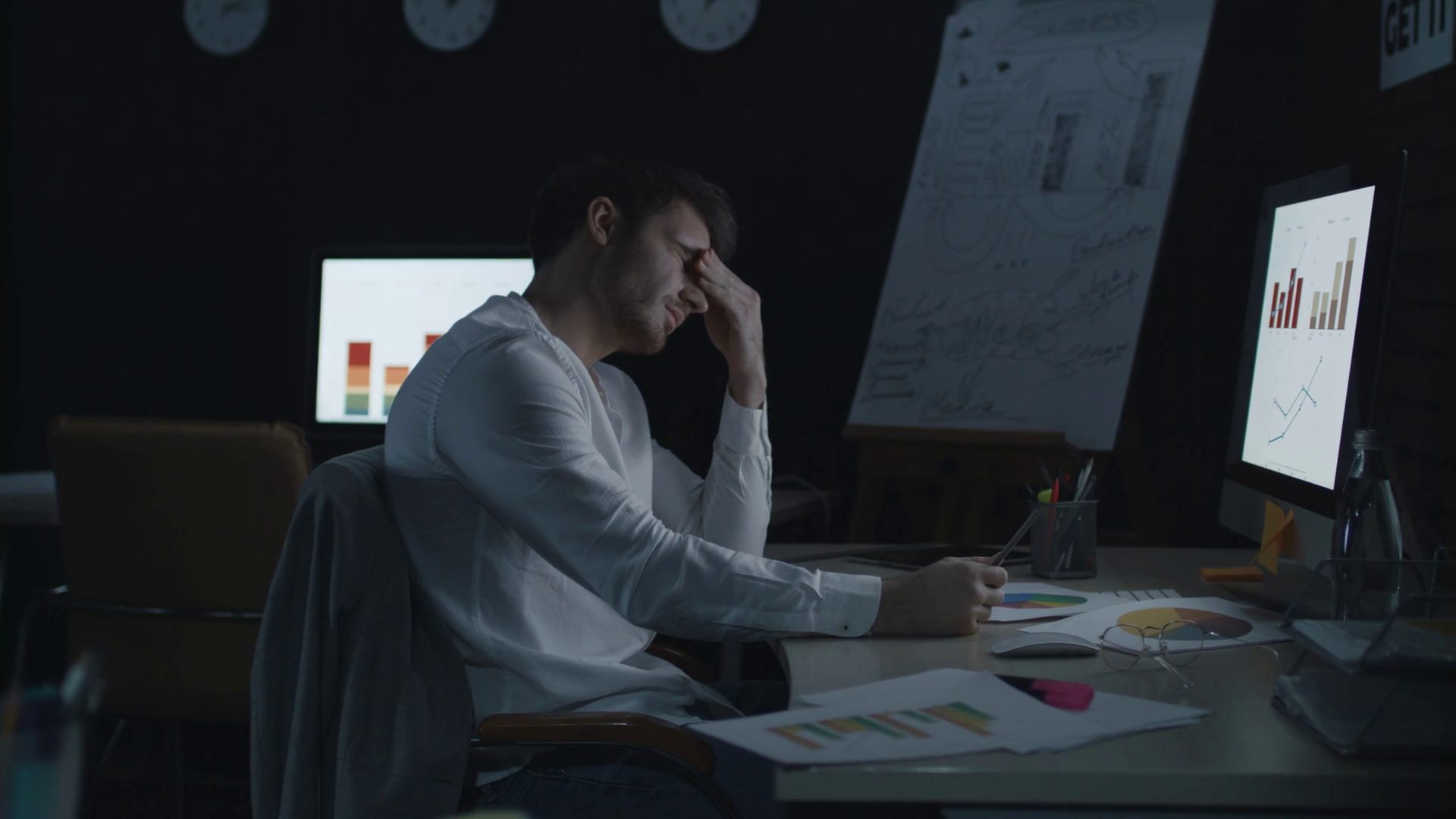 Unhappy businessman browsing business graphs and charts in night office ...