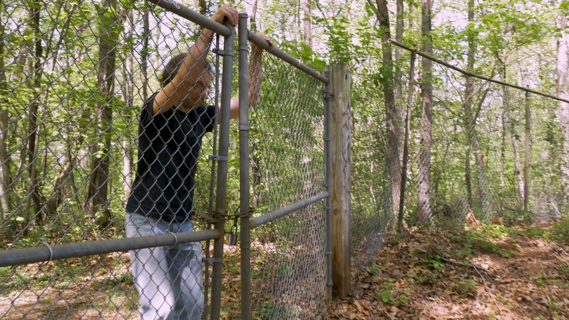 A man in his 30s or 40s being chased quickly climbs over a chain link ...