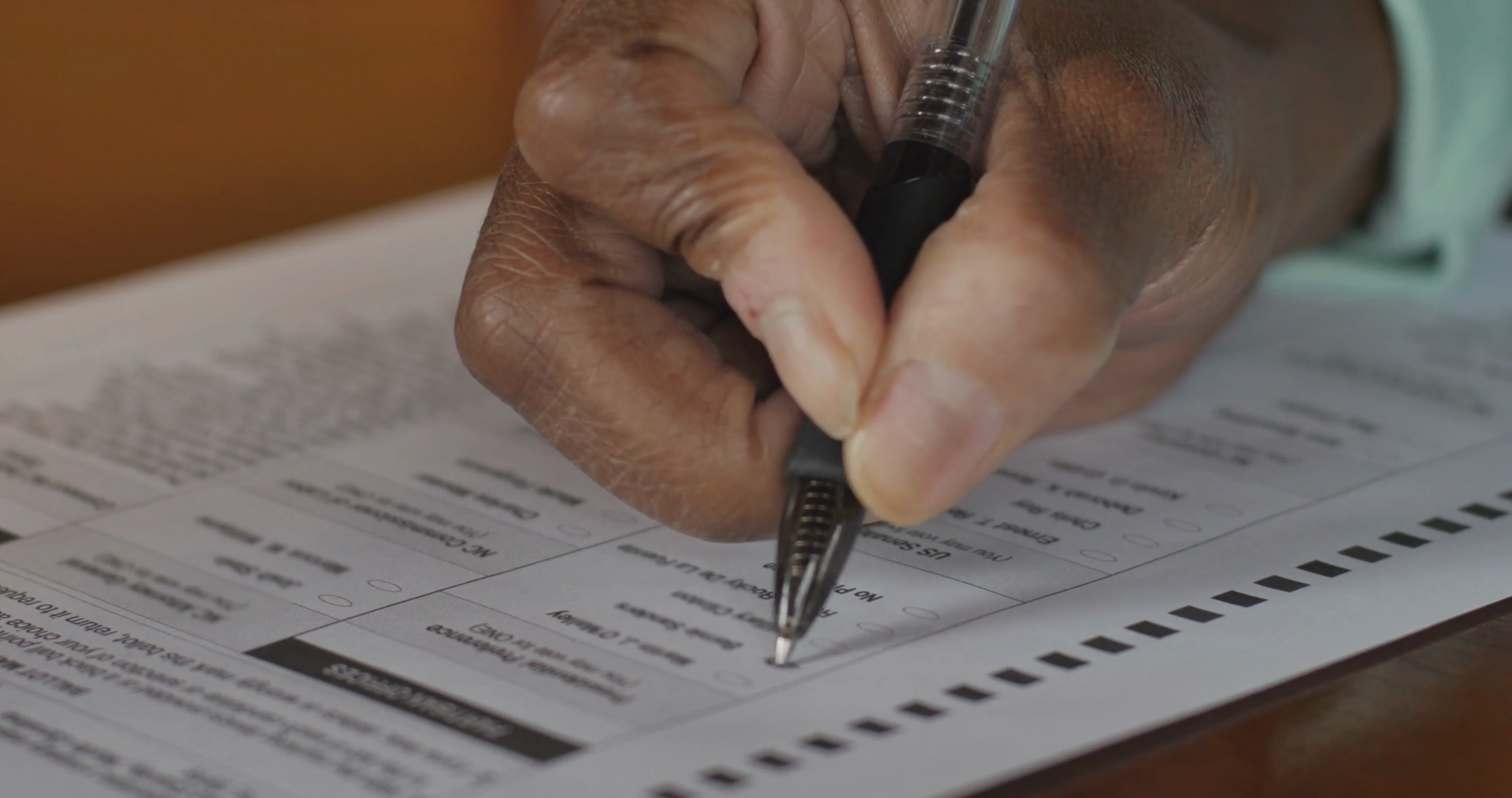 African American woman's hand filling in a voter ballot for a general ...