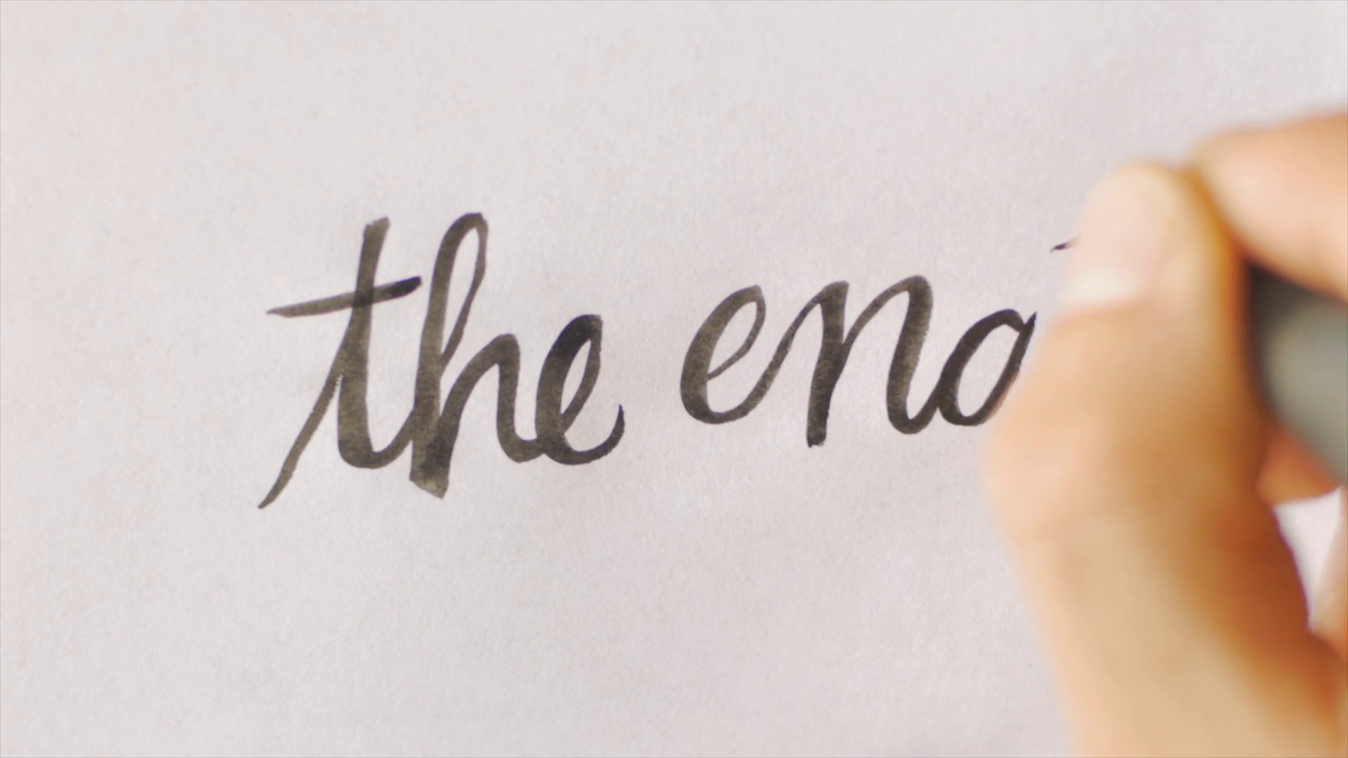 Hand drawing the words THE END and underlining them on white paper in ...