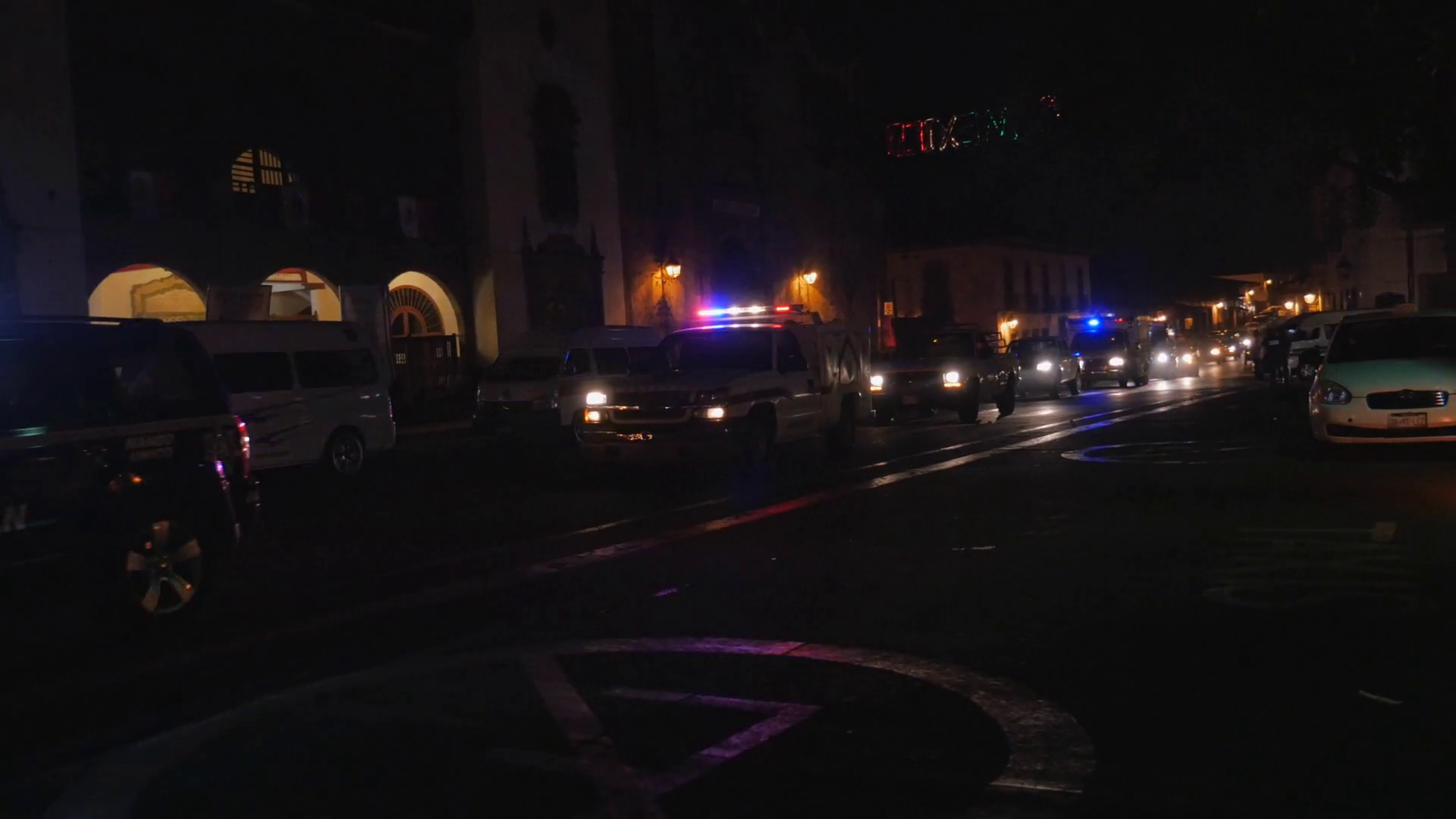 Police cars driving slowly down a street with their strobing blue and ...