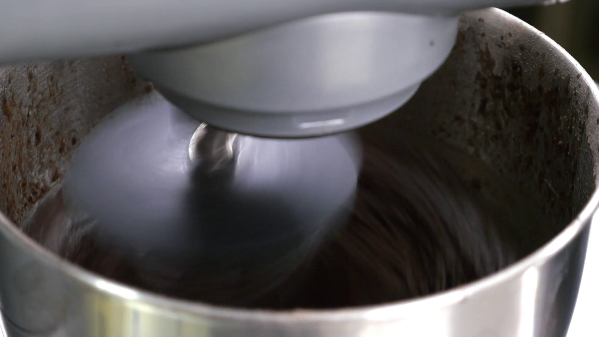 A confectioner mixing a cake mixture with a stand mixer with pouring ...