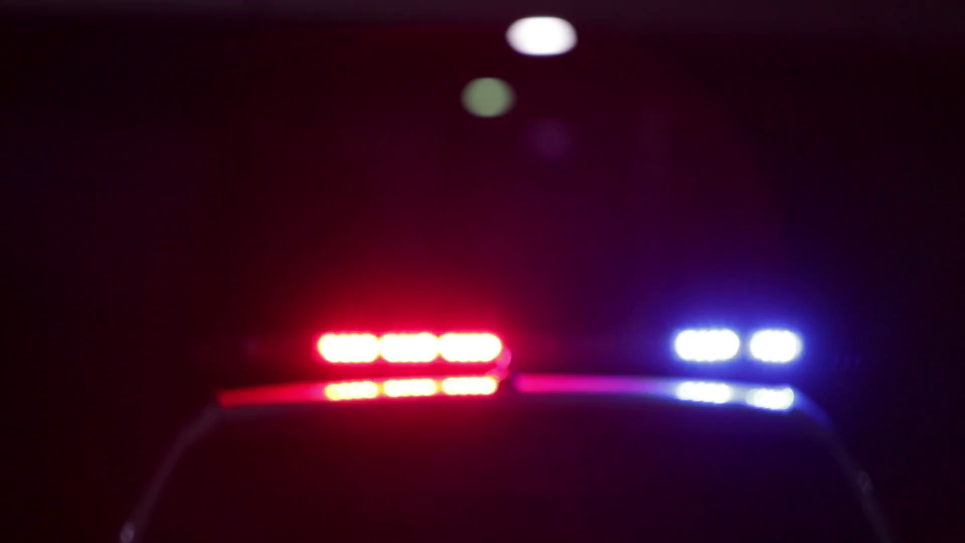 Footage of a crime scene and a police car with emergency lights turned ...