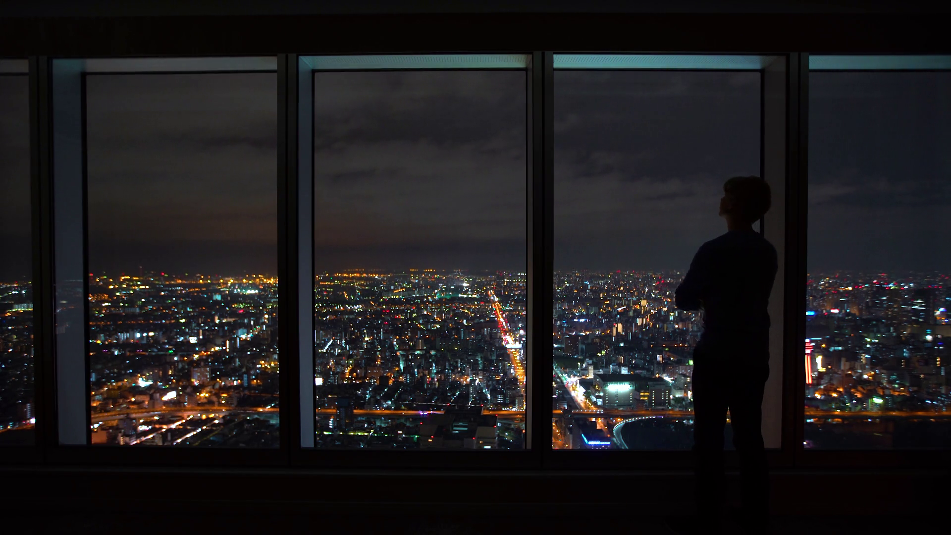 Man looking out large windows high above a sprawling city Stock Video Footage - Storyblocks