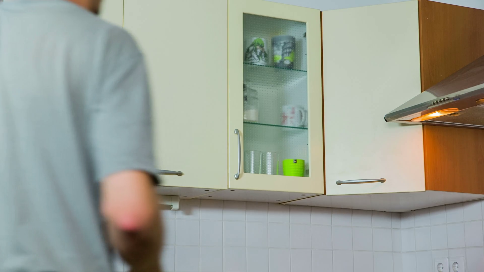 Person takes glass from cupboard. Medium shot of young male reaching in ...