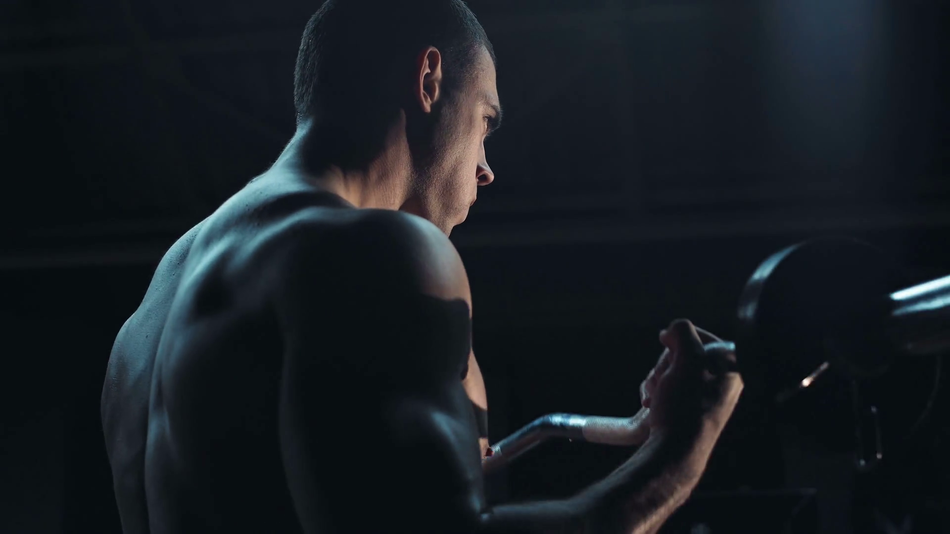 Muscular man doing crossfit training in a dark shadowy gym lifting ...