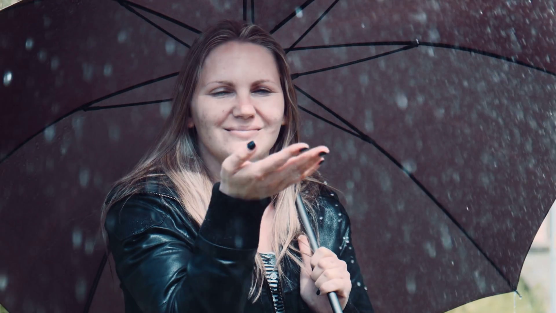 Portrait of smiling blonde adult woman touching rain drops while ...