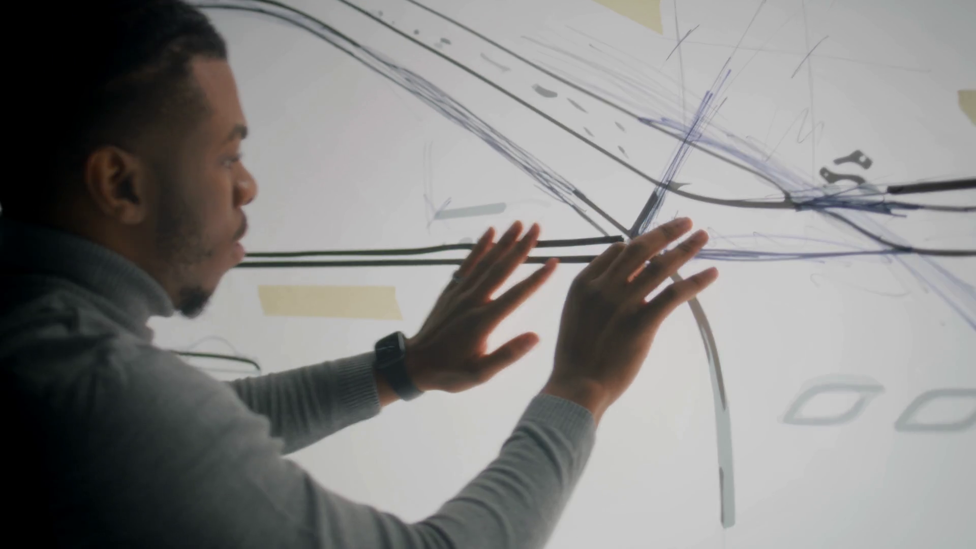 Two diverse automotive male designers creating sketch with duct tape on ...