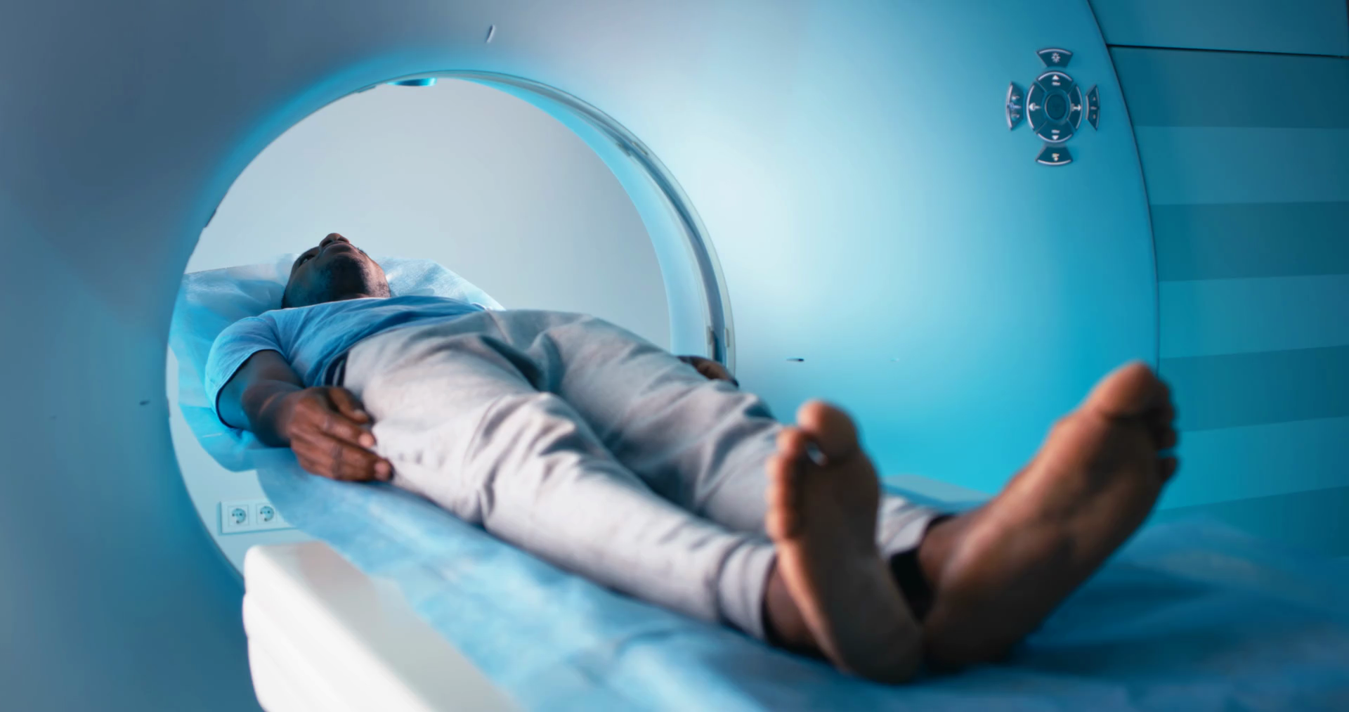 African American man lying in CT machine then crop doctor pushing ...