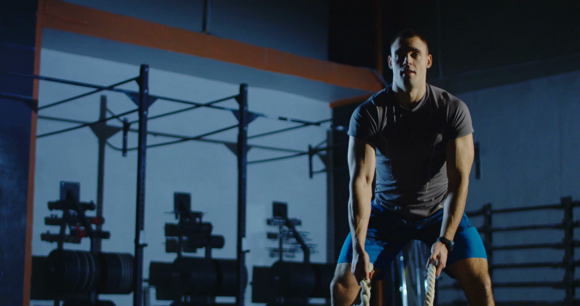 Concentrated sportsman doing hard exercise with heavy ropes while ...