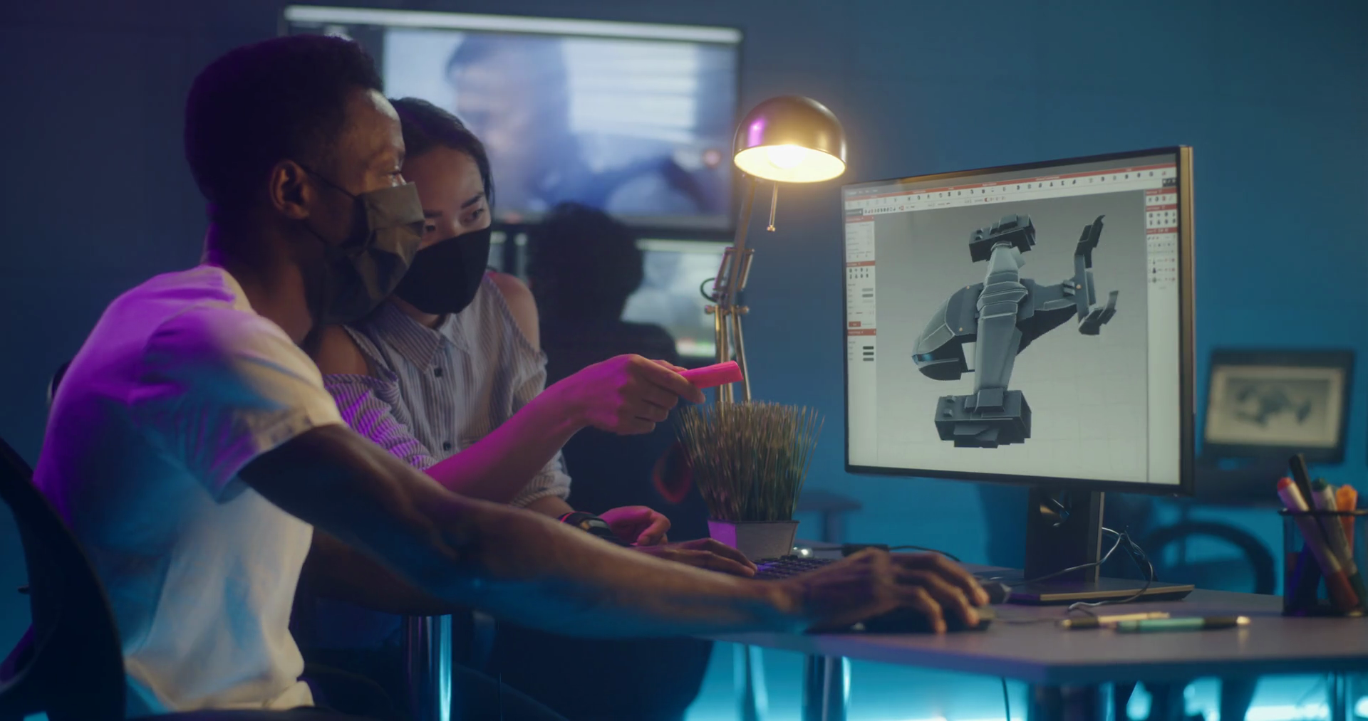 Medium shot of 3d designers discussing a project at their workstation ...