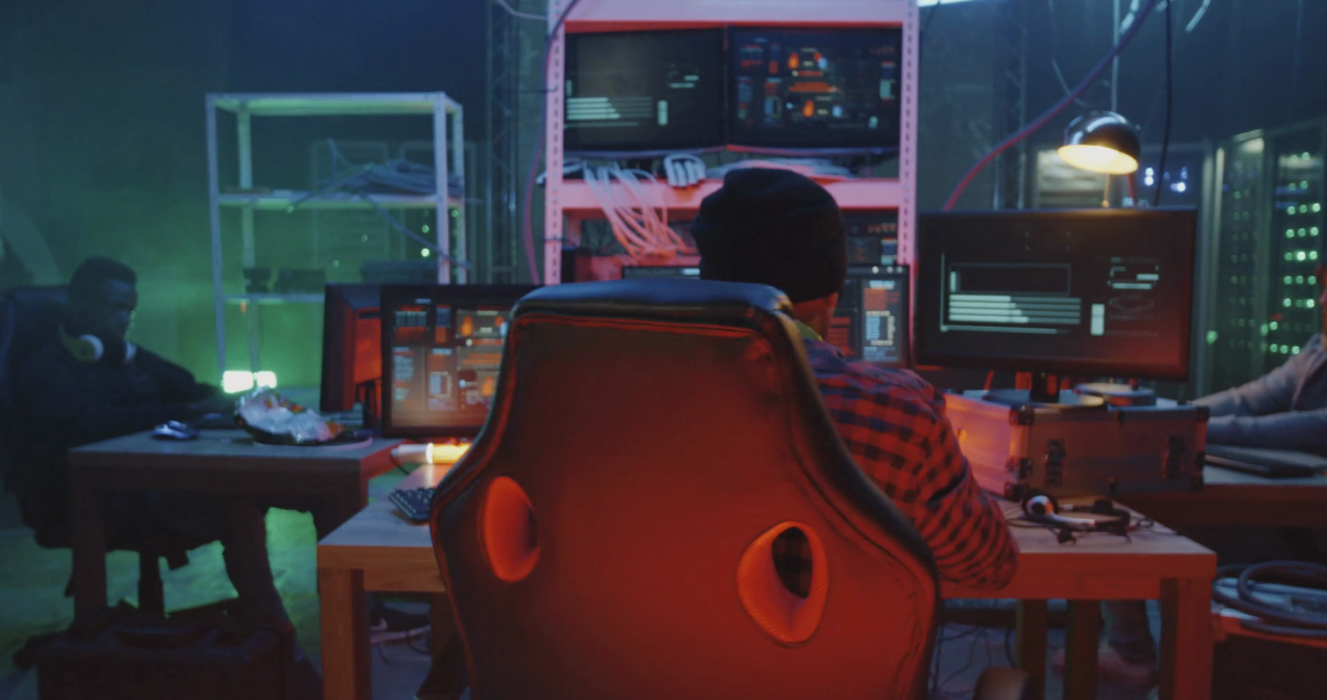 Medium shot of a young male hacker laughing then glaring into camera ...