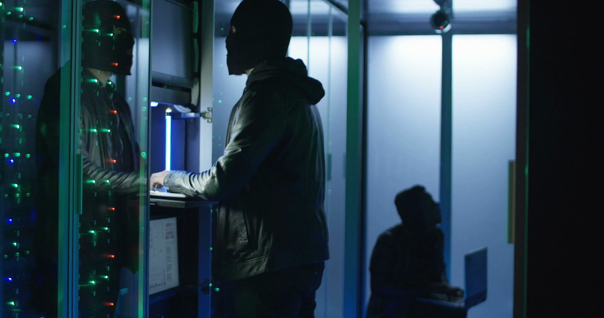 Medium shot of two hackers on laptops in corporate data center then ...
