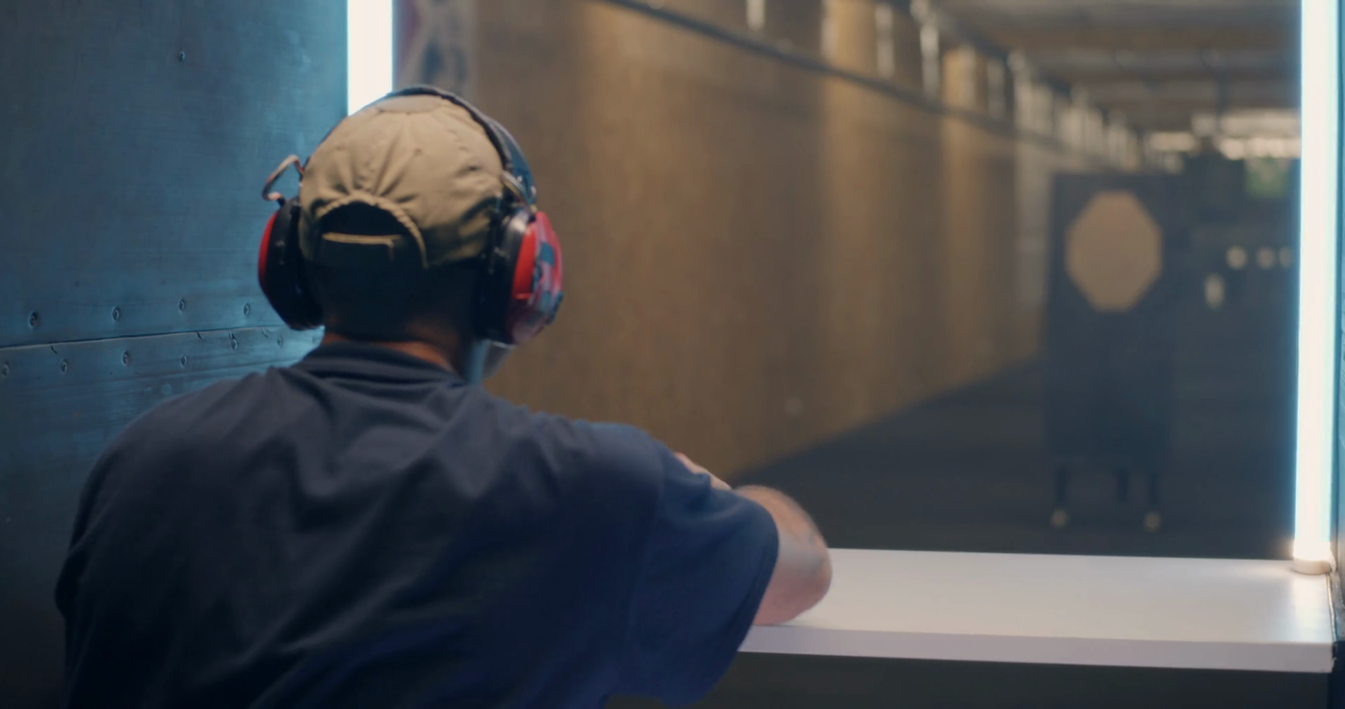 Pan left view of anonymous male shooter reloading and firing pistol at ...