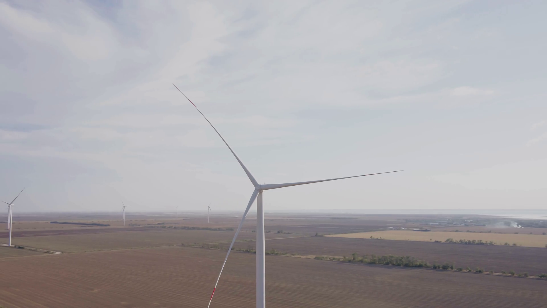 Zoom in drone view of modern windmill located near field on cloudy day ...