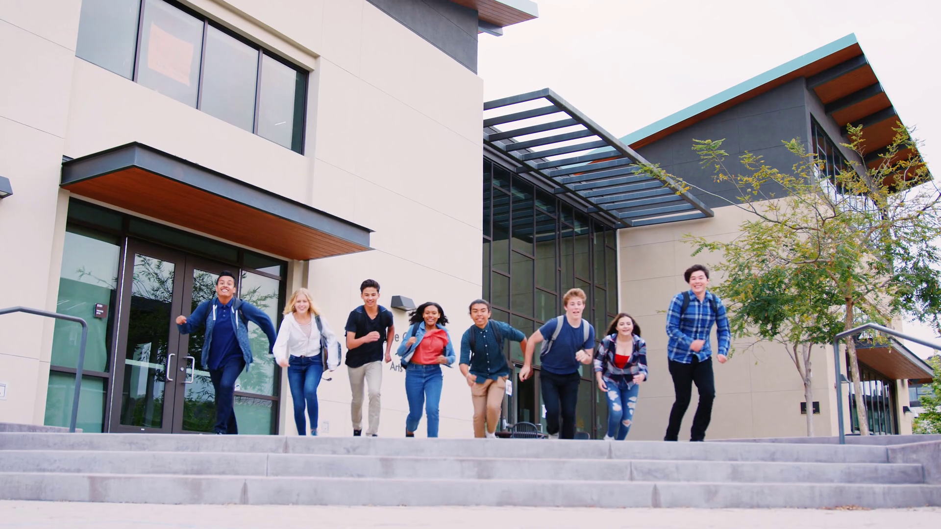 Group Of High School Students Jumping In Air Outside College Buildings ...